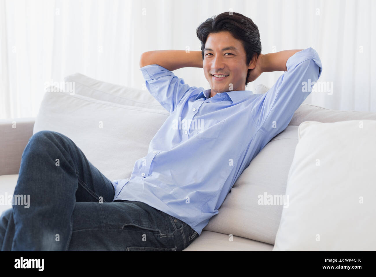 Happy man relaxing on couch at home in the living room Stock Photo - Alamy
