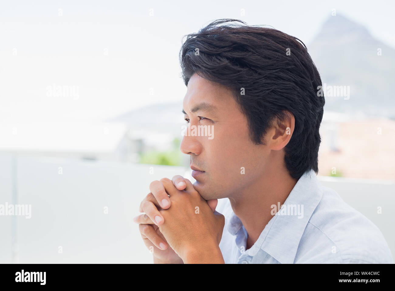 Thinking man with hands together outside on a balcony Stock Photo - Alamy