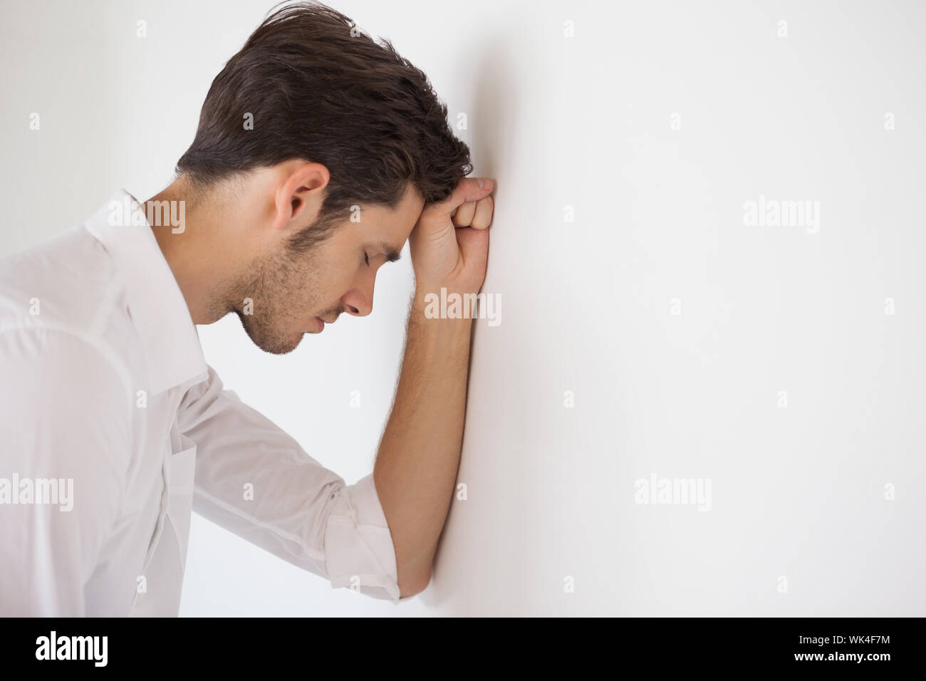 Casual businessman leaning against the wall in his office Stock Photo ...