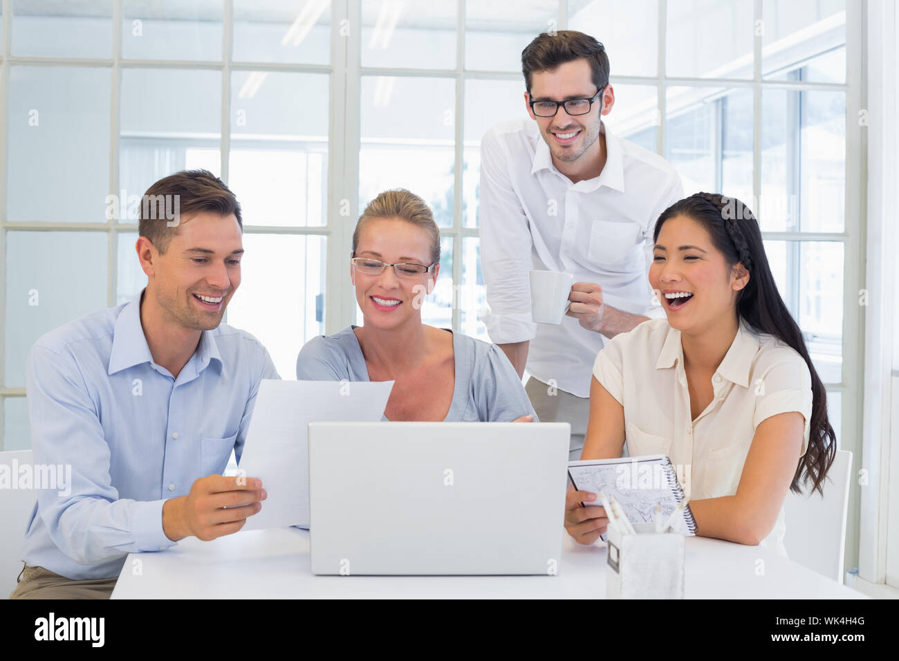 Casual business team laughing together at desk in the office Stock ...