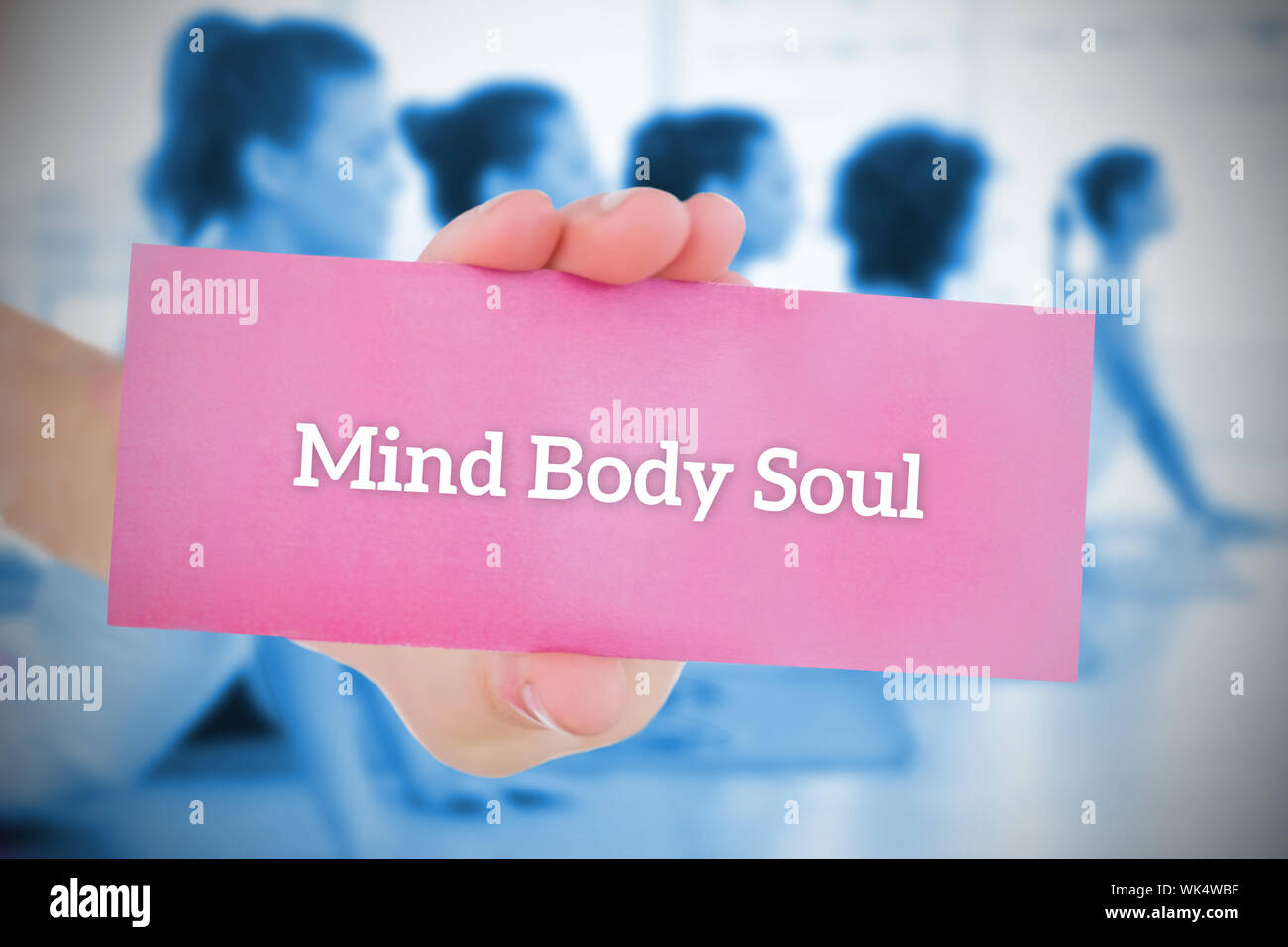 Woman holding pink card saying mind body soul against yoga class in gym ...