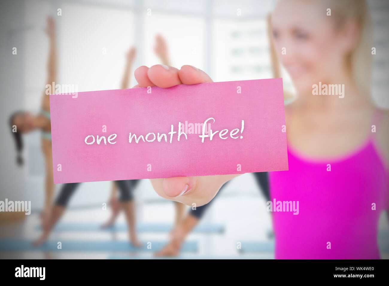 Fit blonde holding card saying one month free against fitness class in ...
