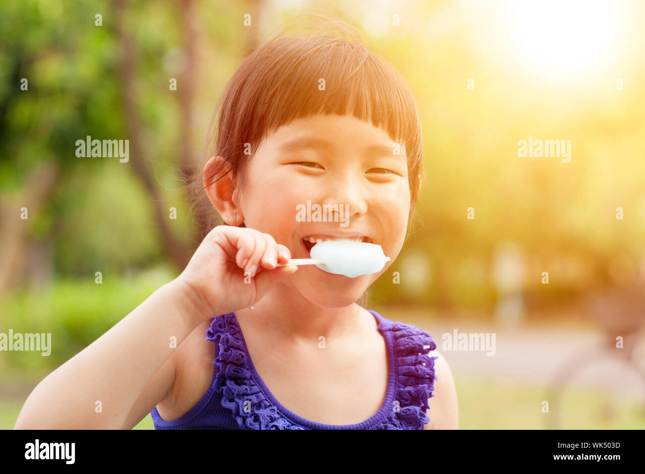 happy little girl eating popsicle with sunset background Stock Photo ...