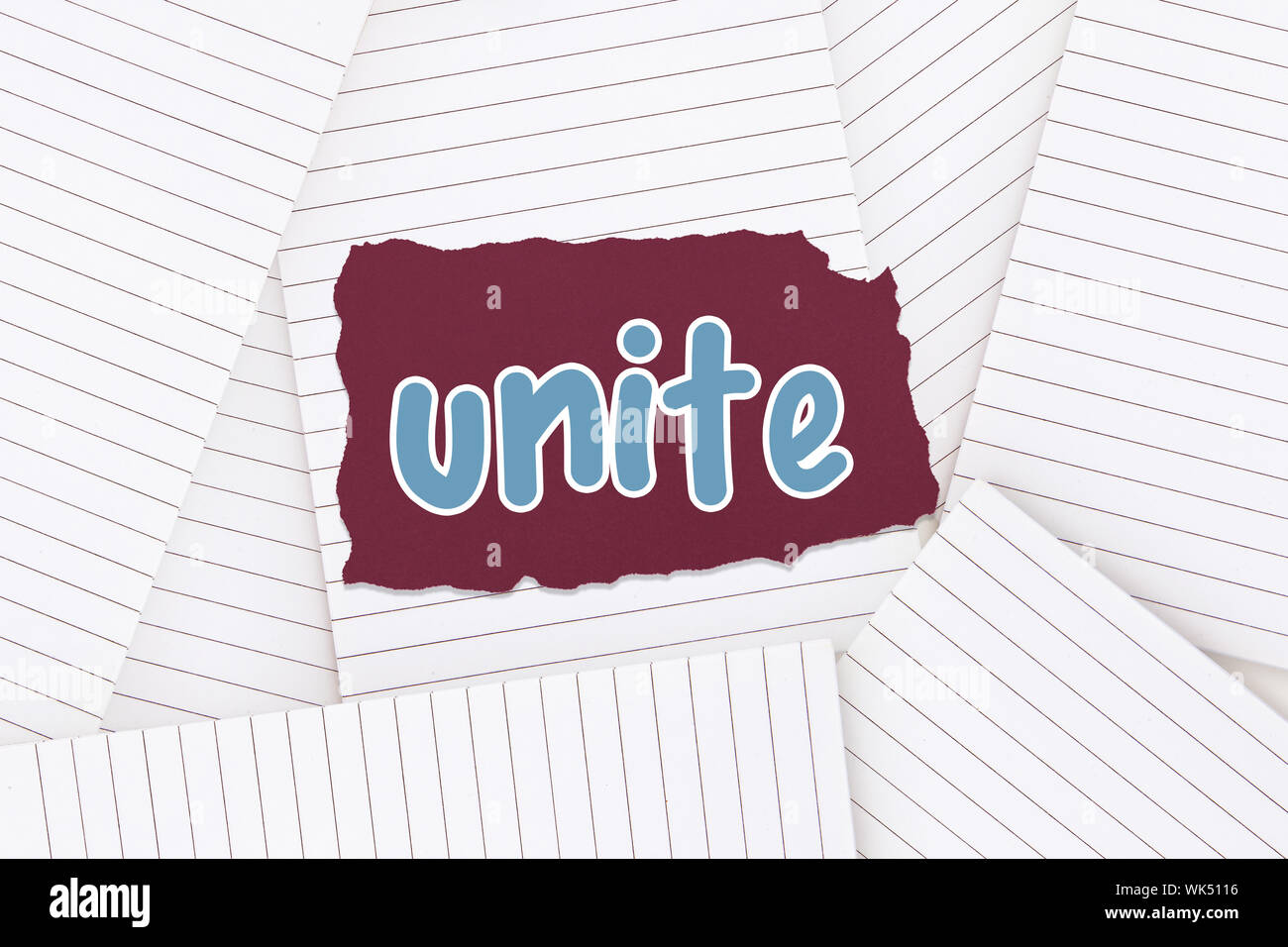 The word unite against lined paper strewn over surface Stock Photo - Alamy
