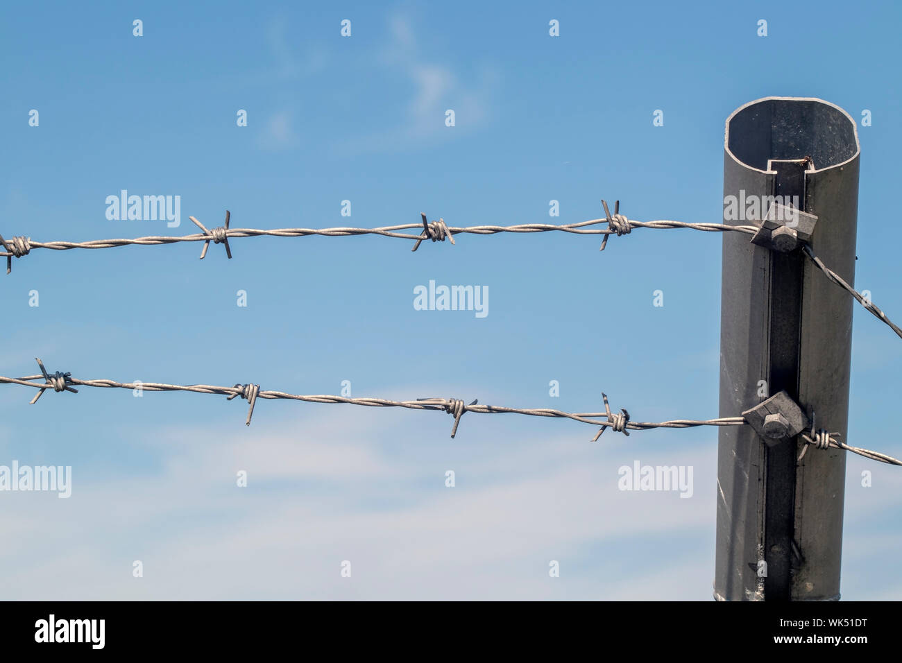 barbed wire lines against blue sky Stock Photo - Alamy