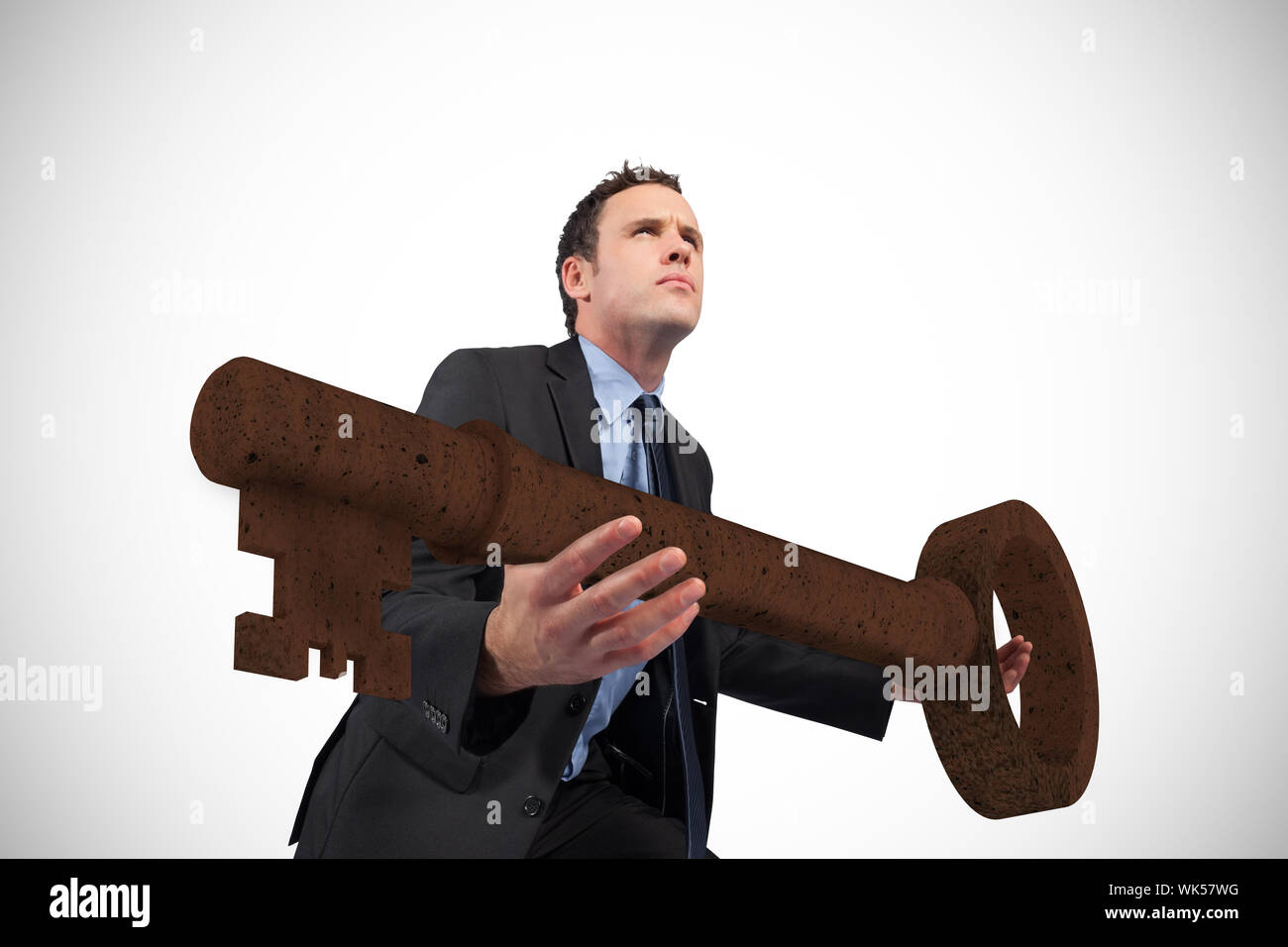 Businessman carrying large key with arms out against white background ...