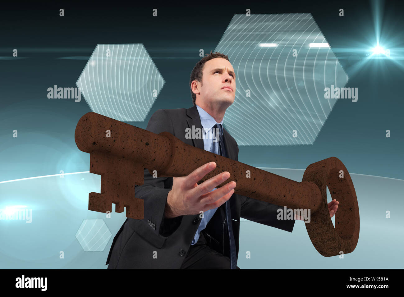 Businessman carrying large key with arms out against hexagon interface ...