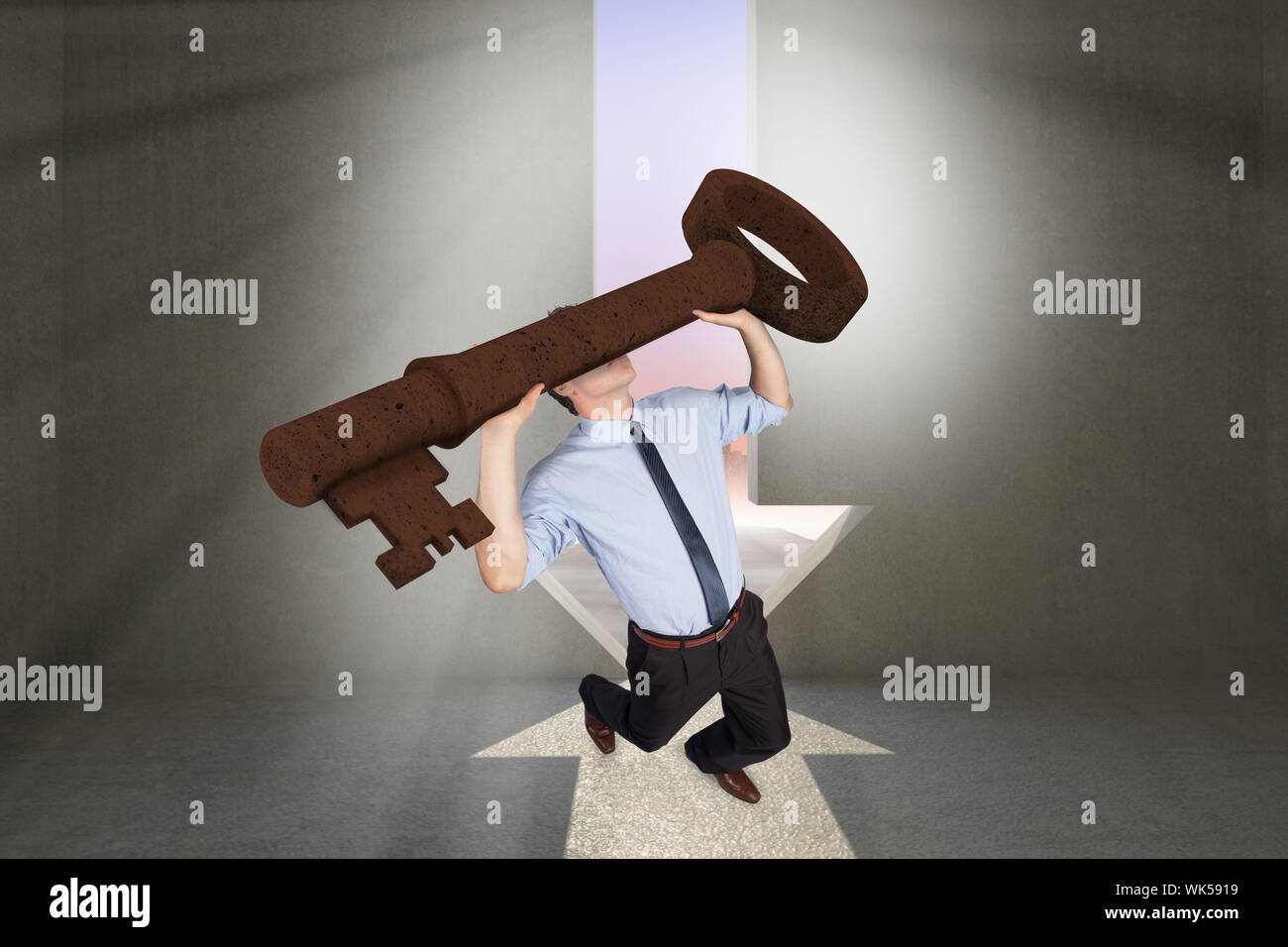 Businessman carrying large key with arms raised against arrow door in ...