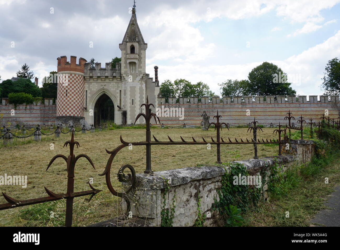 old stone and brick entrance and wall of a castle with black wrought ...