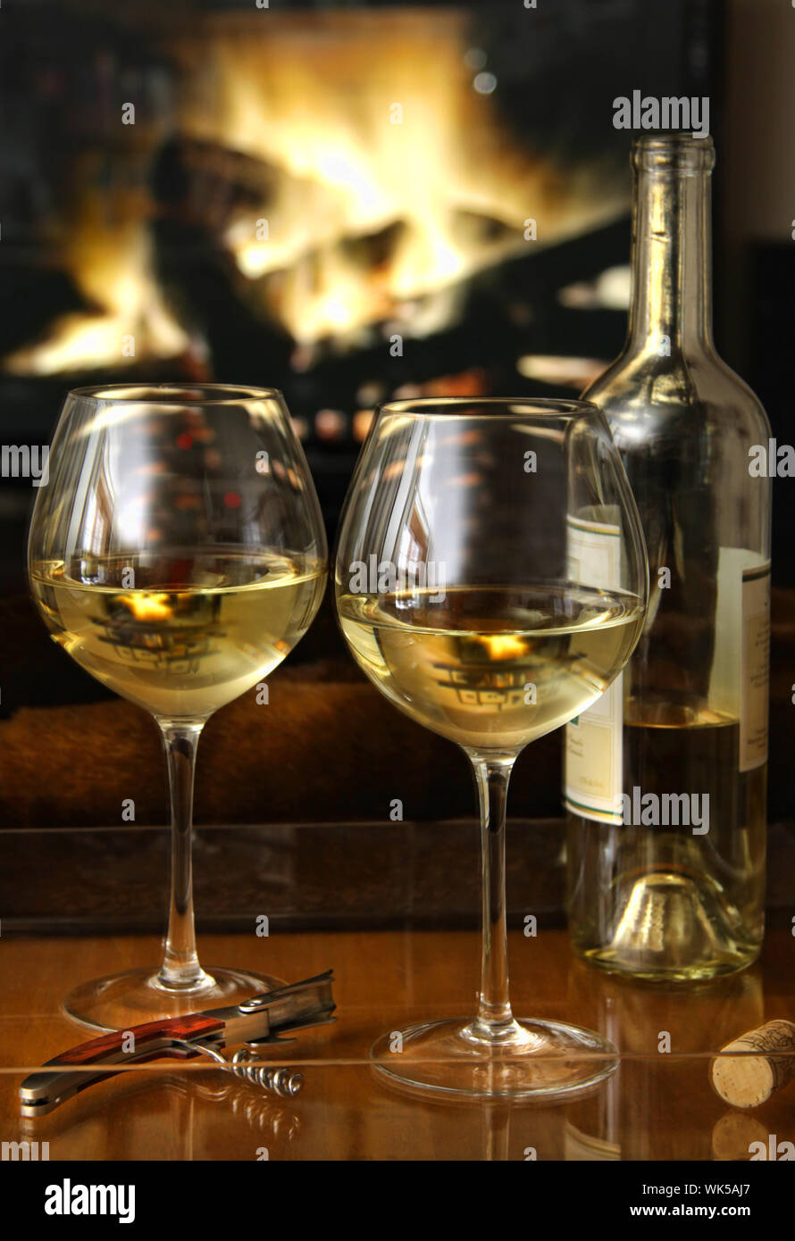 Enjoying glasses of white wine in front of a warm fire Stock Photo - Alamy