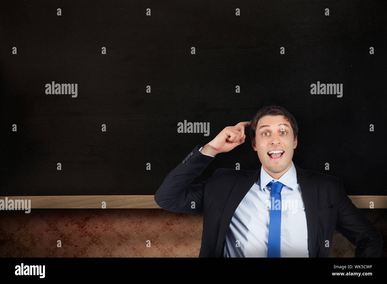 Thinking businessman scratching head against chalkboard on brown ...