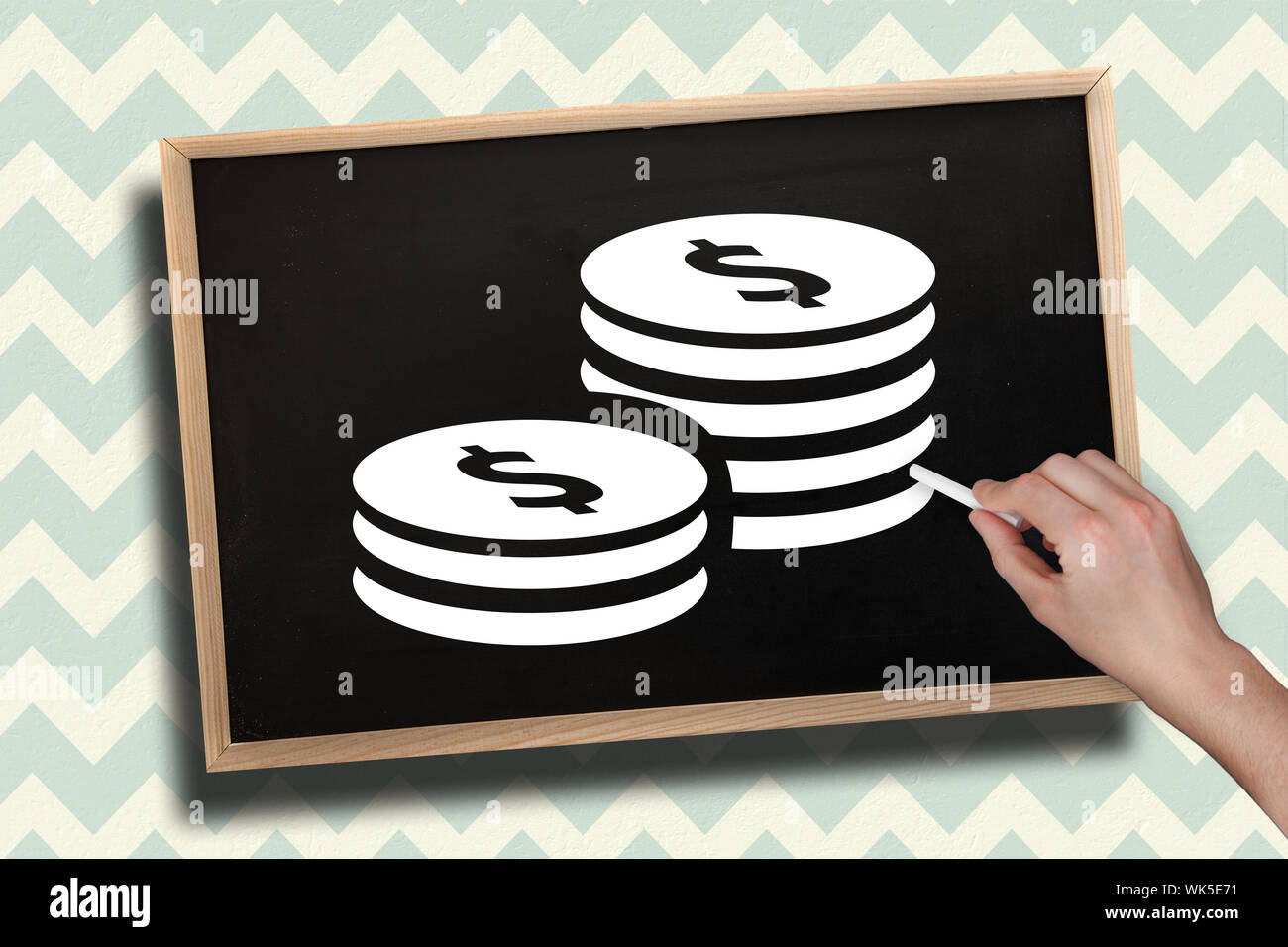 Composite image of hand drawing coins with chalk on chalkboard with ...