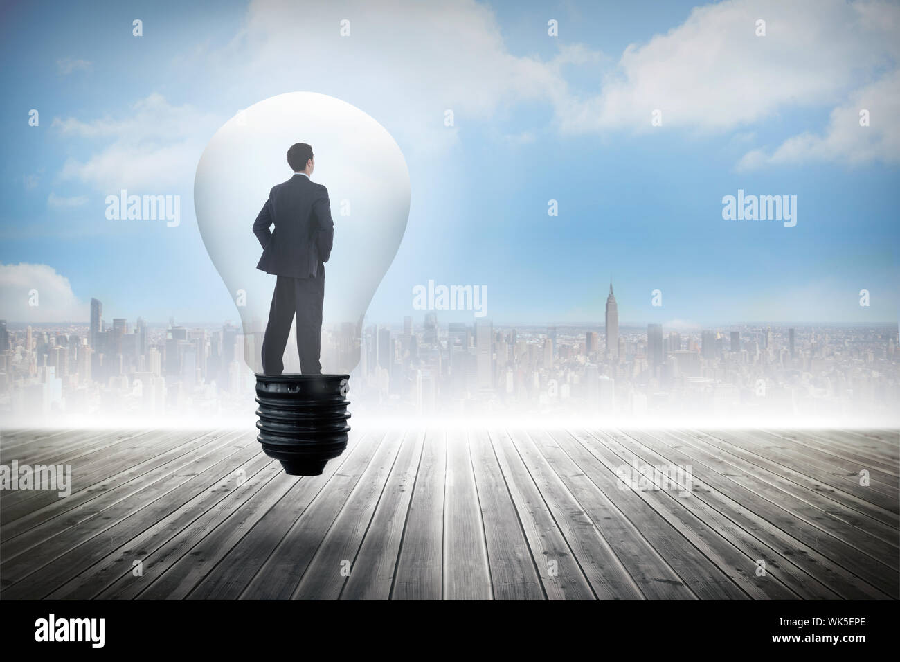 Thinking businessman in light bulb against cityscape on the horizon ...