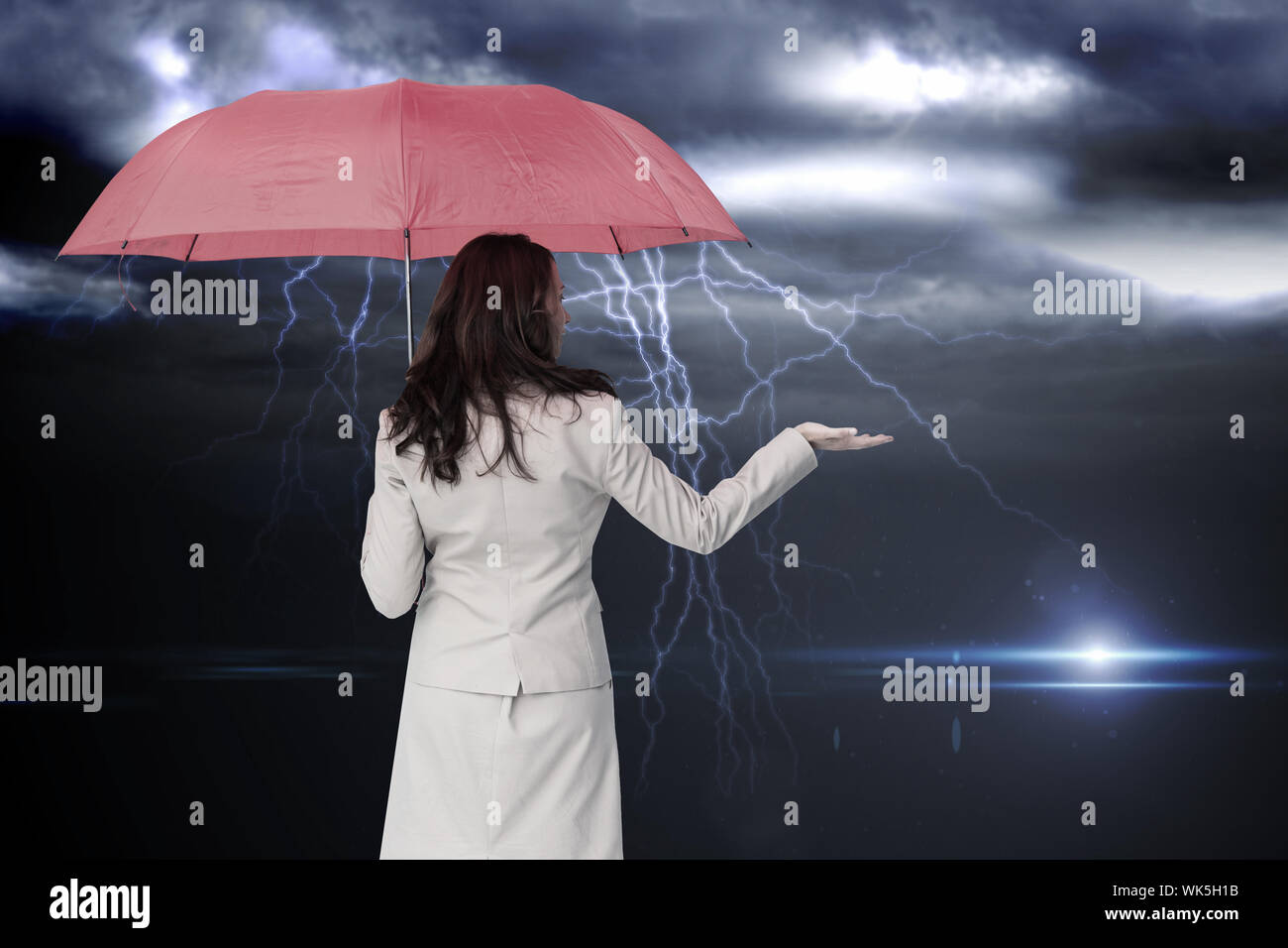 Businesswoman holding umbrella against stormy dark sky with lightning ...
