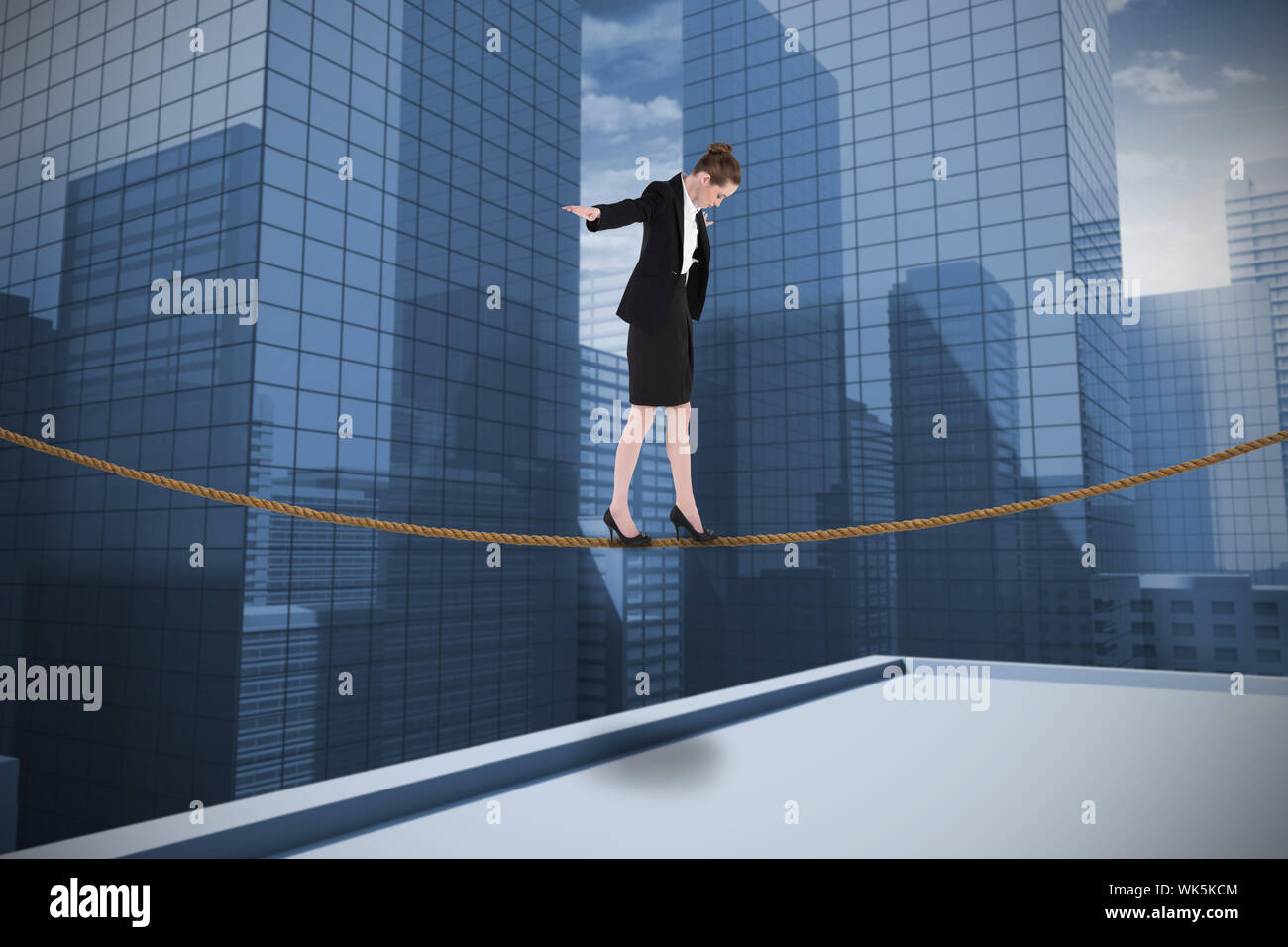 Businesswoman performing a balancing act against view of dull cityscape ...