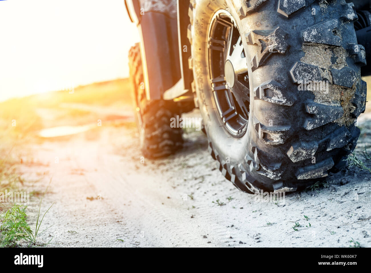 Close-up tail view of ATV quad bike on dirt country road at evening ...