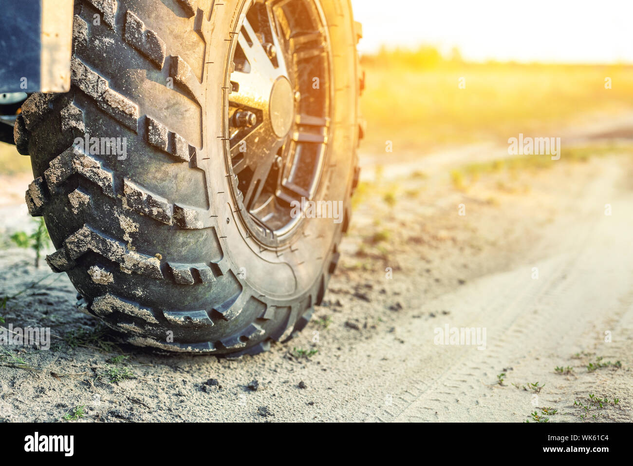 Close-up tail view of ATV quad bike on dirt country road at evening ...