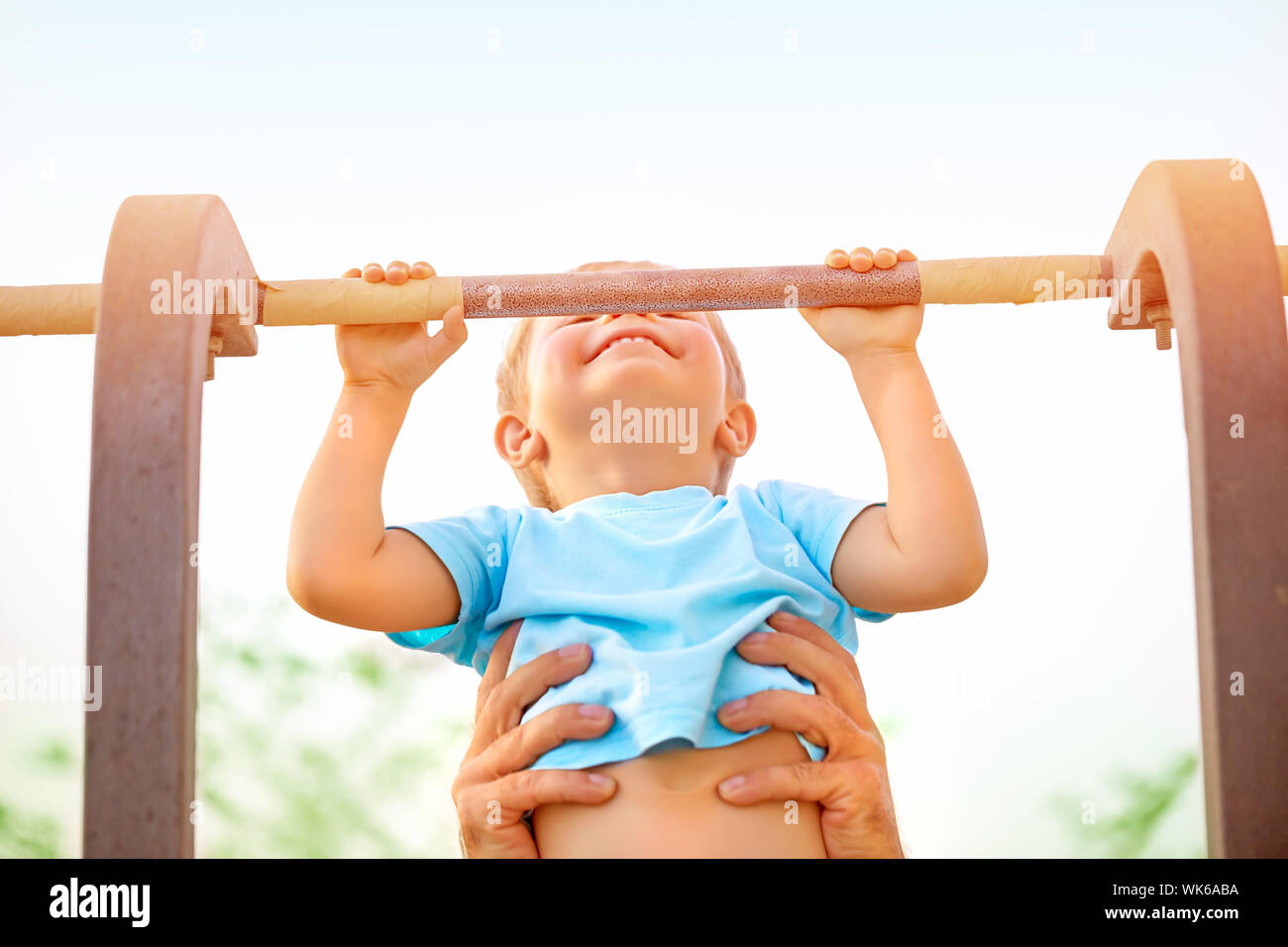 Little boy with fathers help catch up on the horizontal bar, active ...