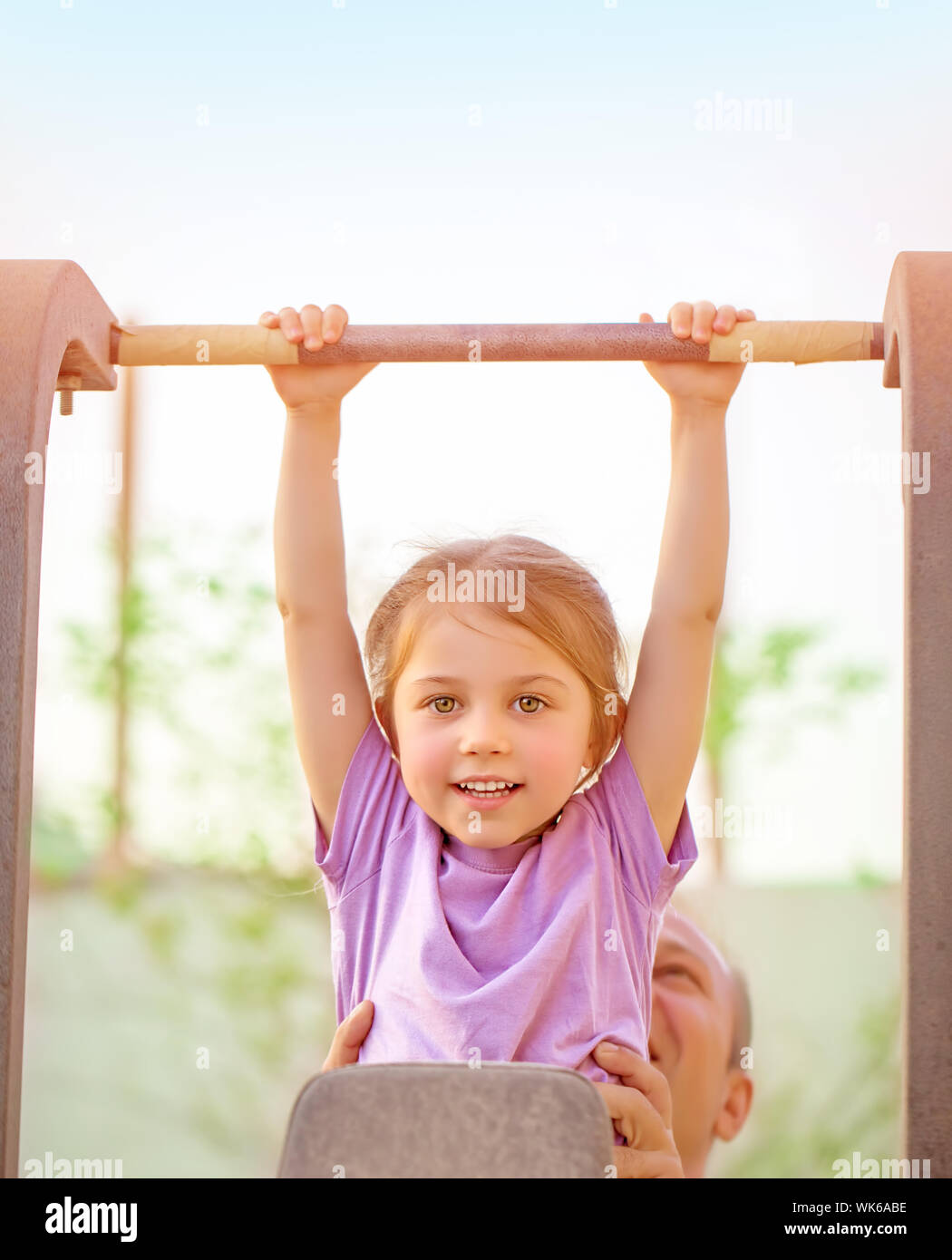 Closeup portrait of little happy girl lifting on crossbar, daddy help ...