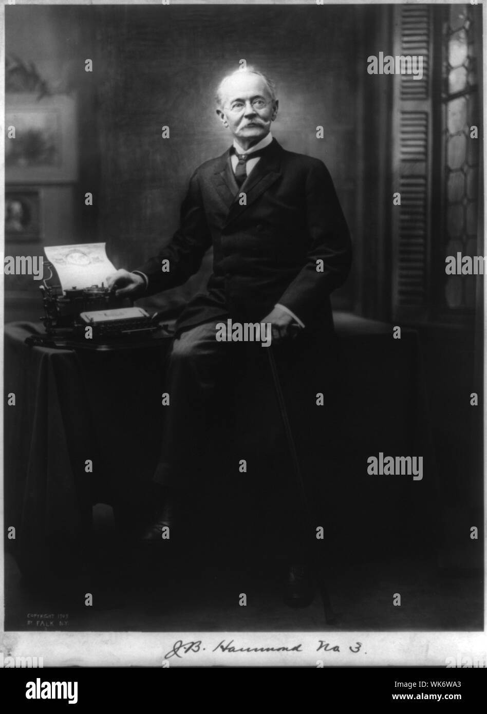 J.B. Hammond, full length portrait, seated on table, facing front; with ...