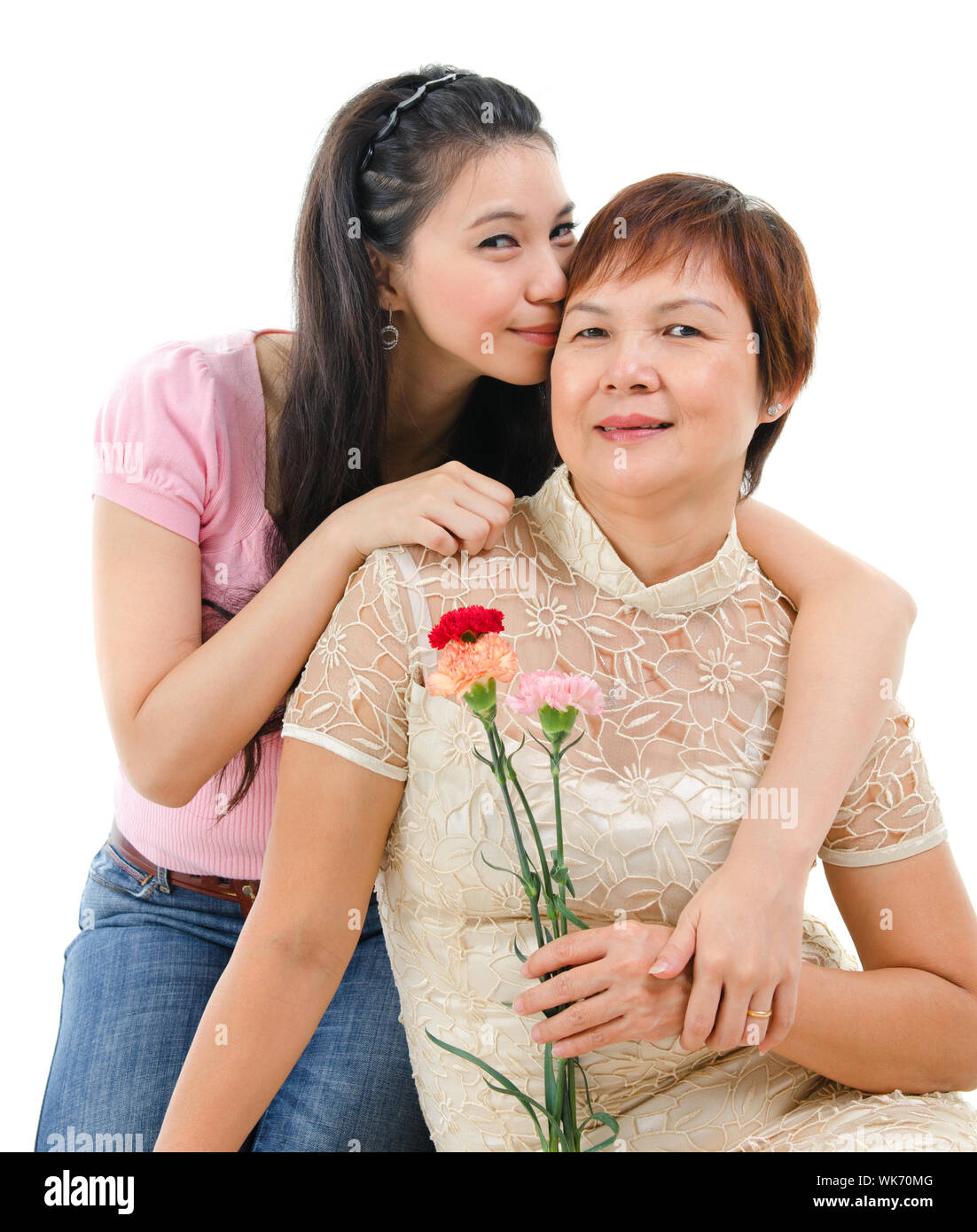 Senior mother holding carnation flower, adult daughter embraces and ...
