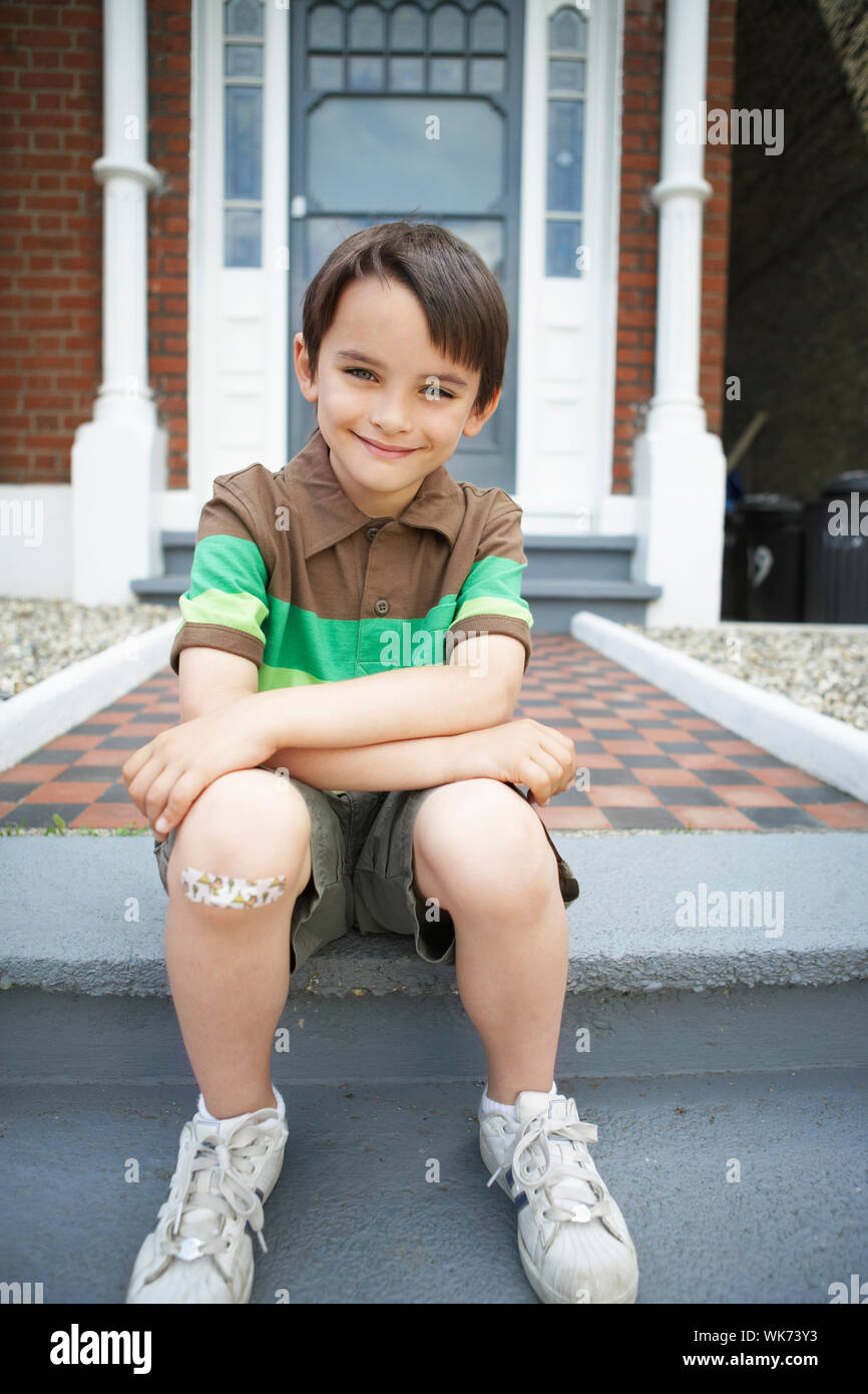 Portrait of happy little boy sitting on front steps of house Stock ...