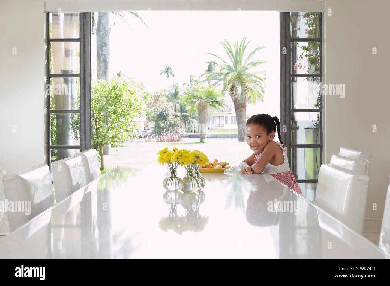 Portrait of happy little girl sitting at dining table Stock Photo - Alamy