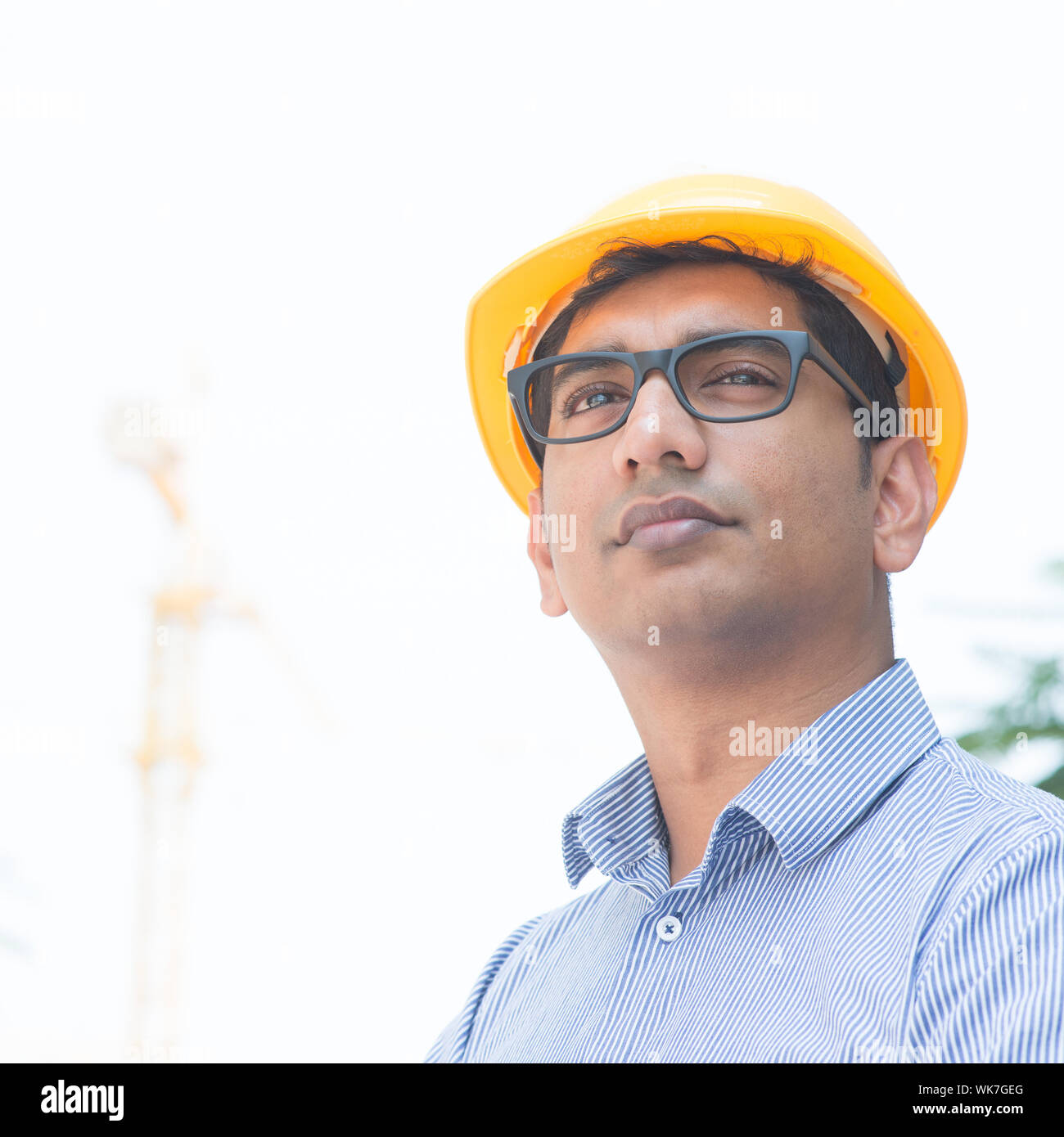 Portrait of an Asian Indian engineer looking away, standing in front ...