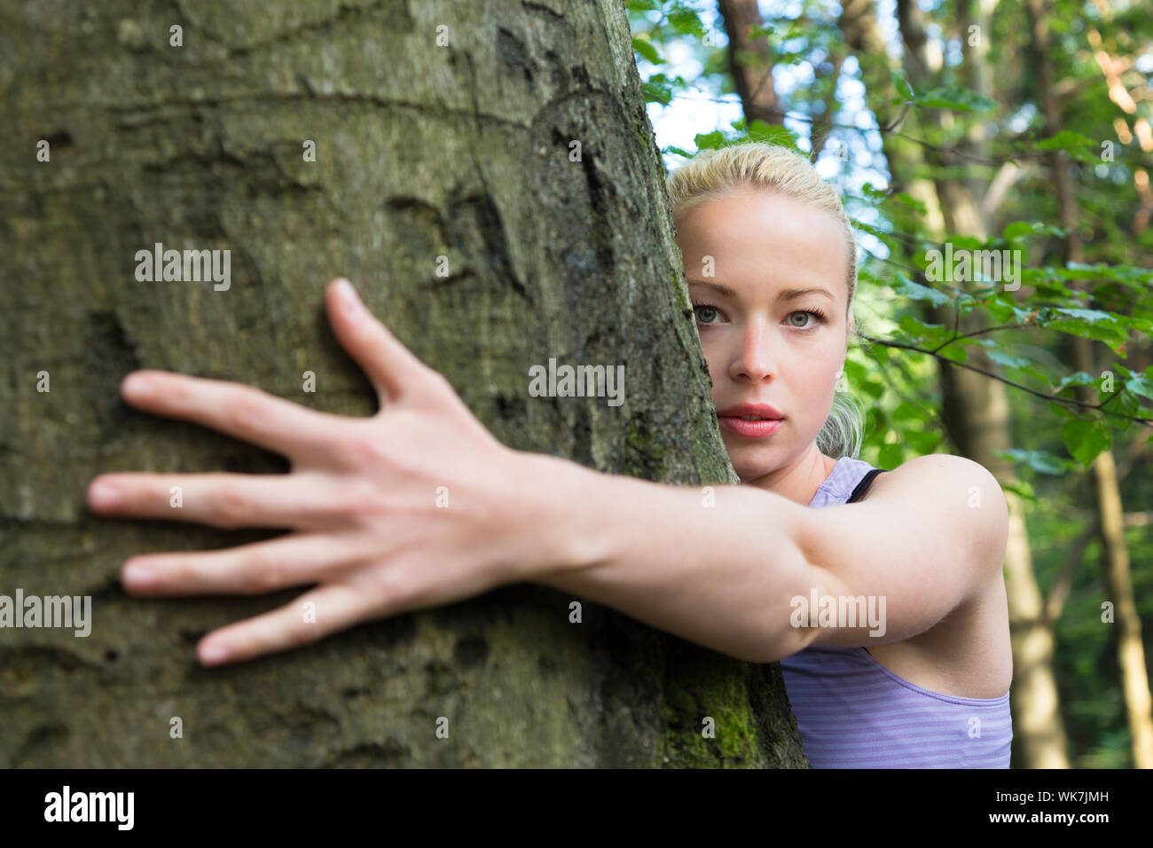 Relaxed young lady embracing a tree receiving life energy from the ...