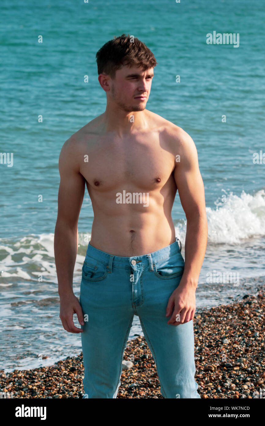 Young shirtless muscular caucasian man, posing on a beach on a warm ...