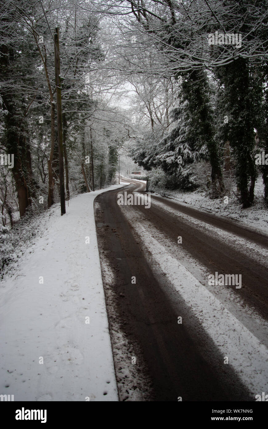 Snow-covered road and pavement with slushy tracks going into the ...
