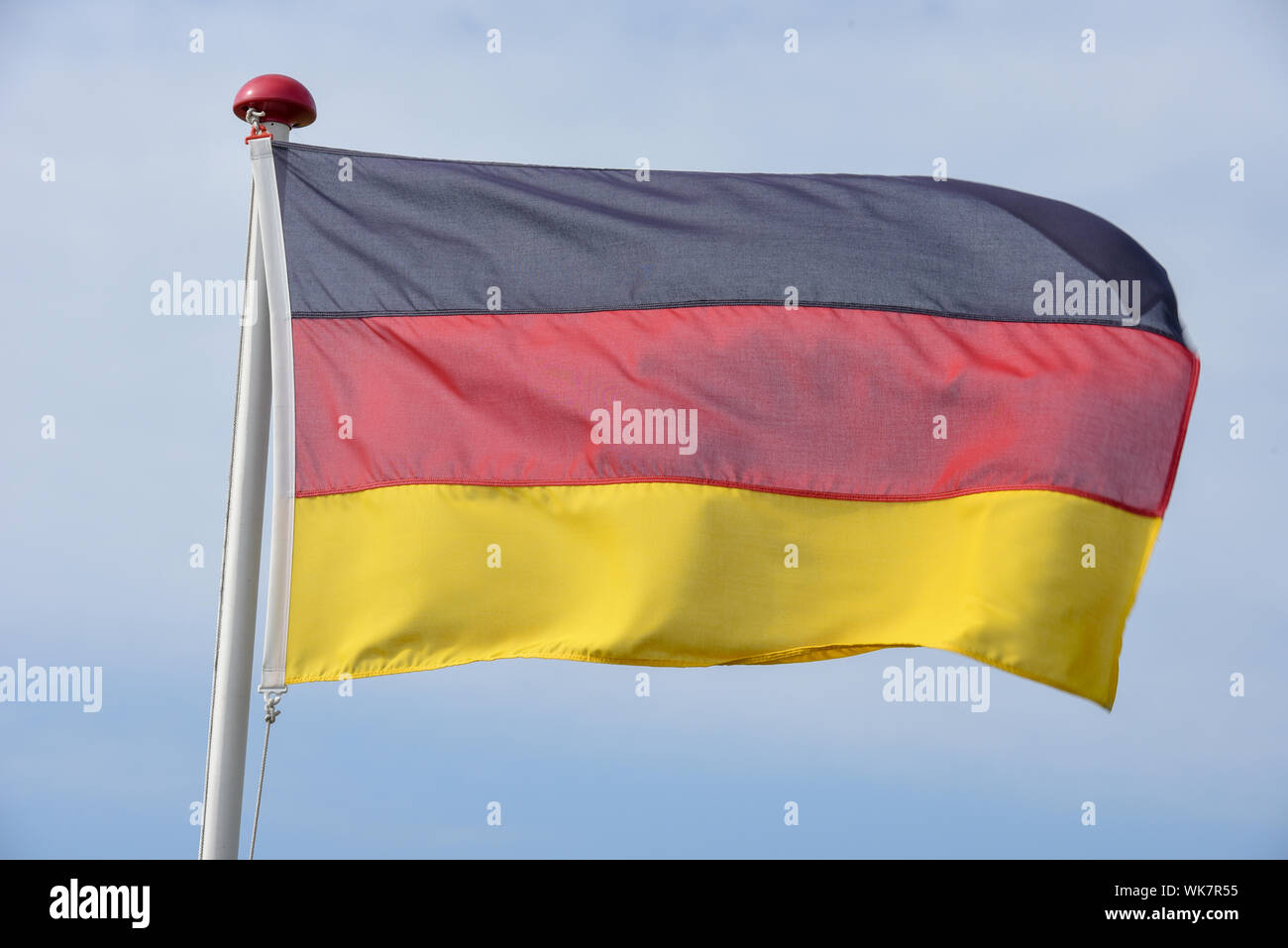 German flag waving on the wind against blue sky Stock Photo - Alamy