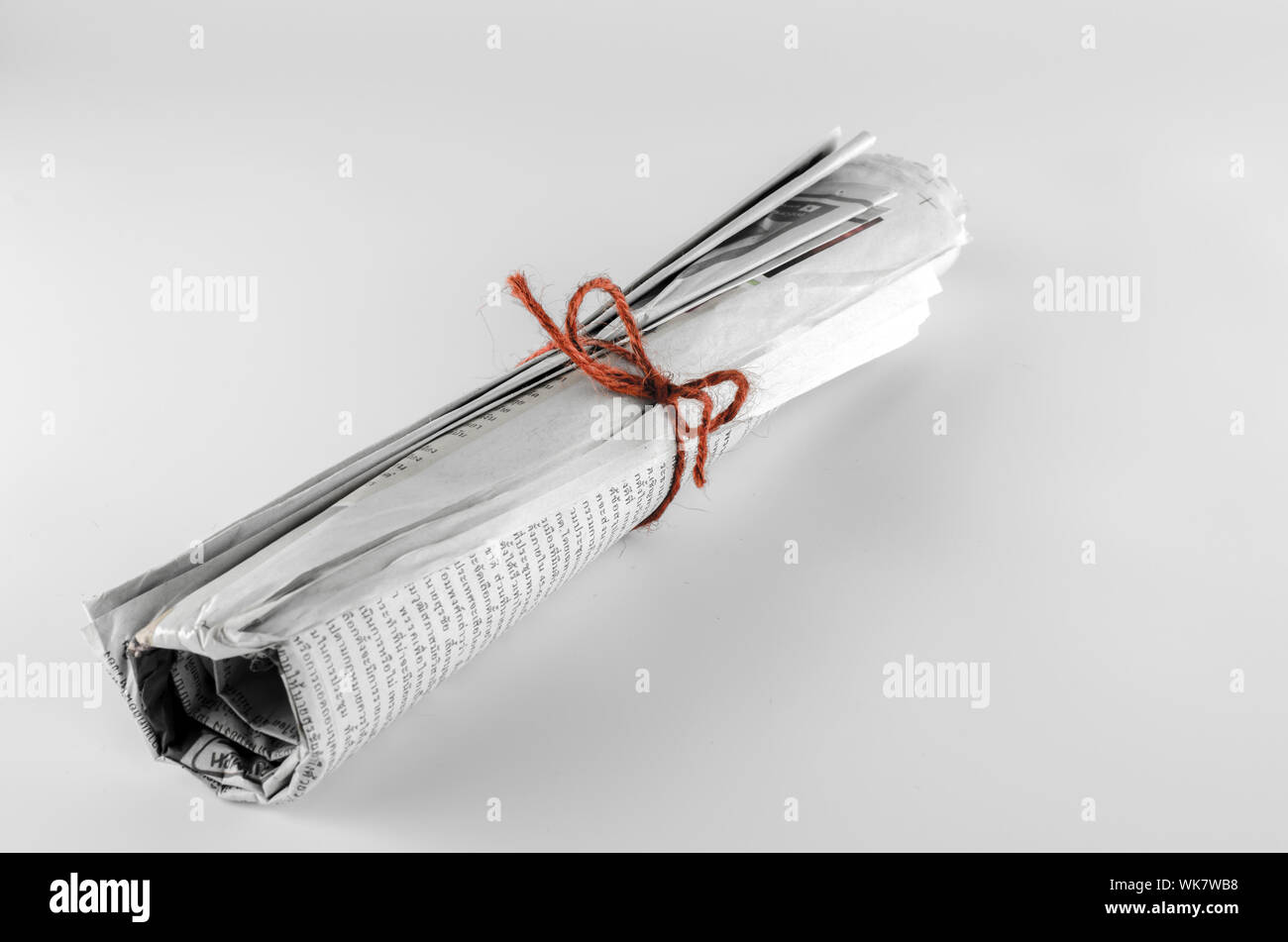 rolled up newspaper focus on red rope on a white background Stock Photo ...