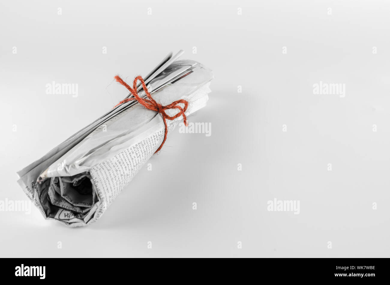 rolled up newspaper focus on red rope on a white background Stock Photo ...