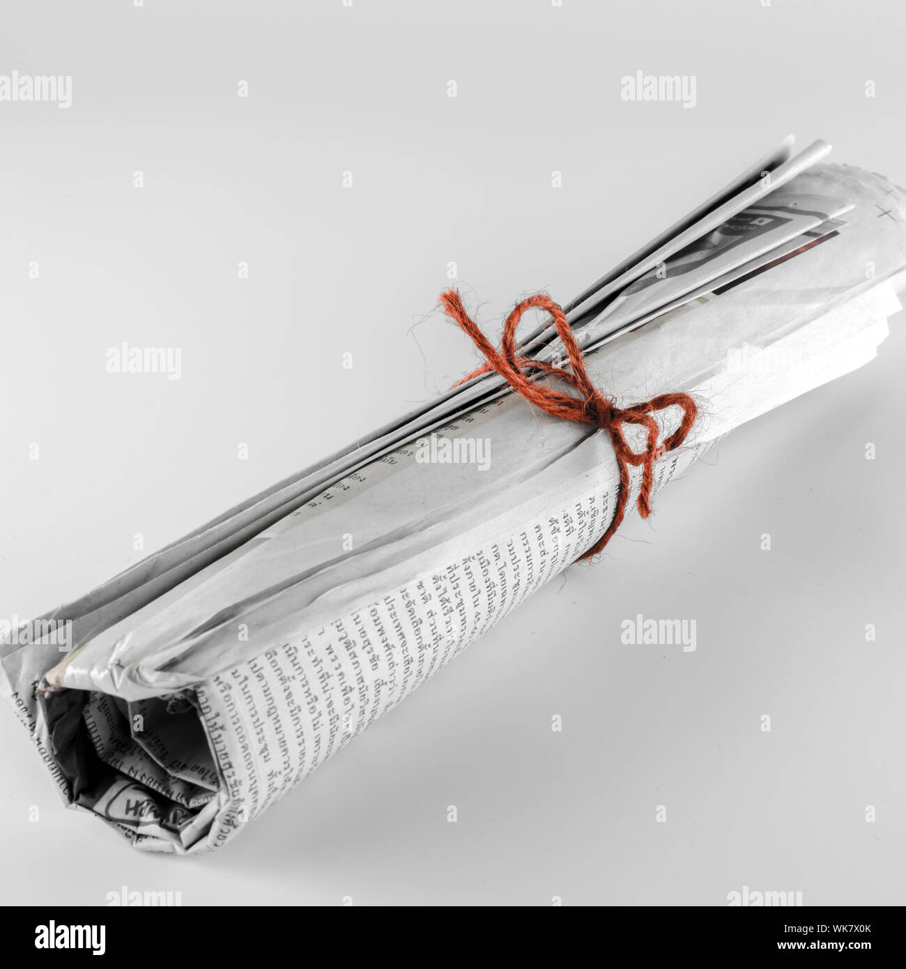 rolled up newspaper focus on red rope on a white background Stock Photo ...