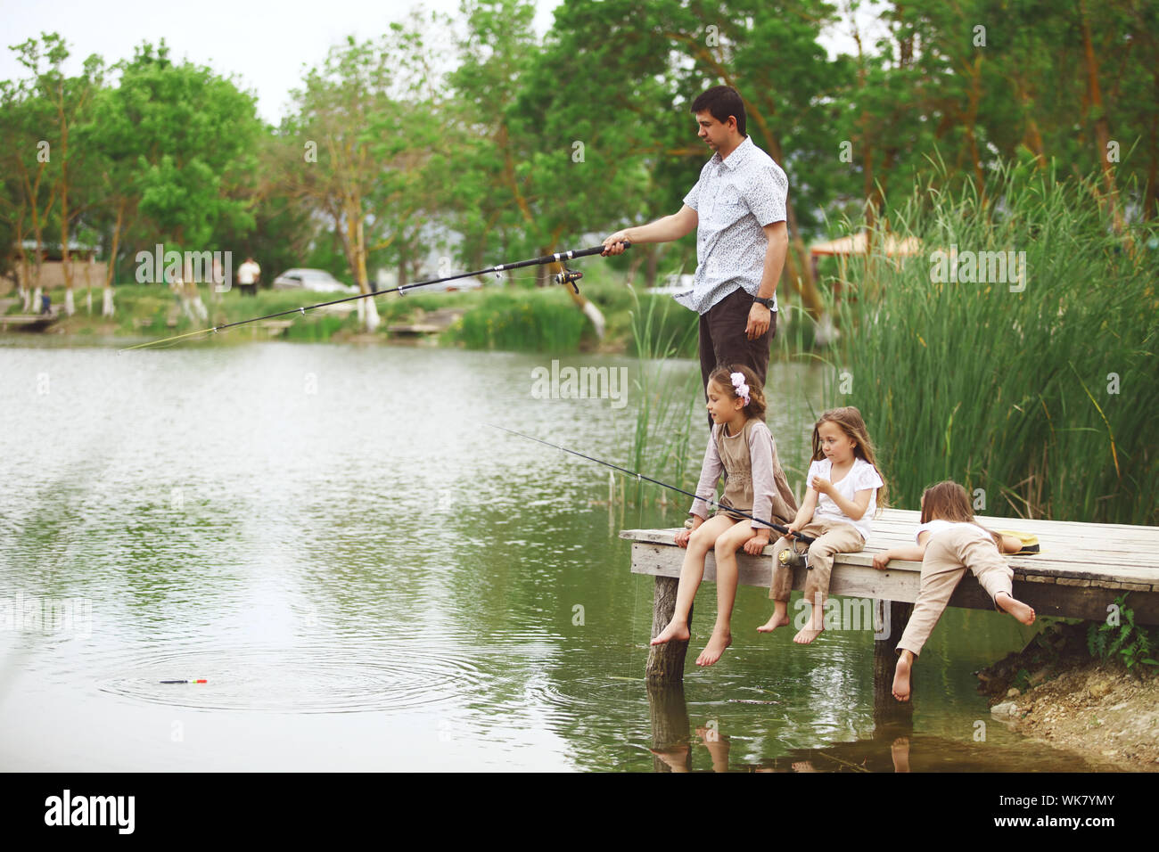 Young happy family with kids fishing in pond in summer Stock Photo - Alamy