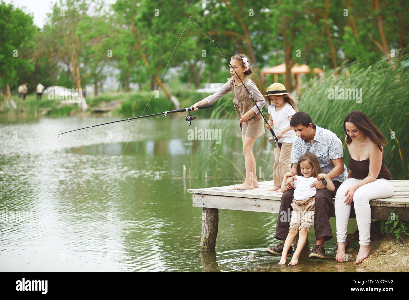 Young happy family with kids fishing in pond in summer Stock Photo - Alamy