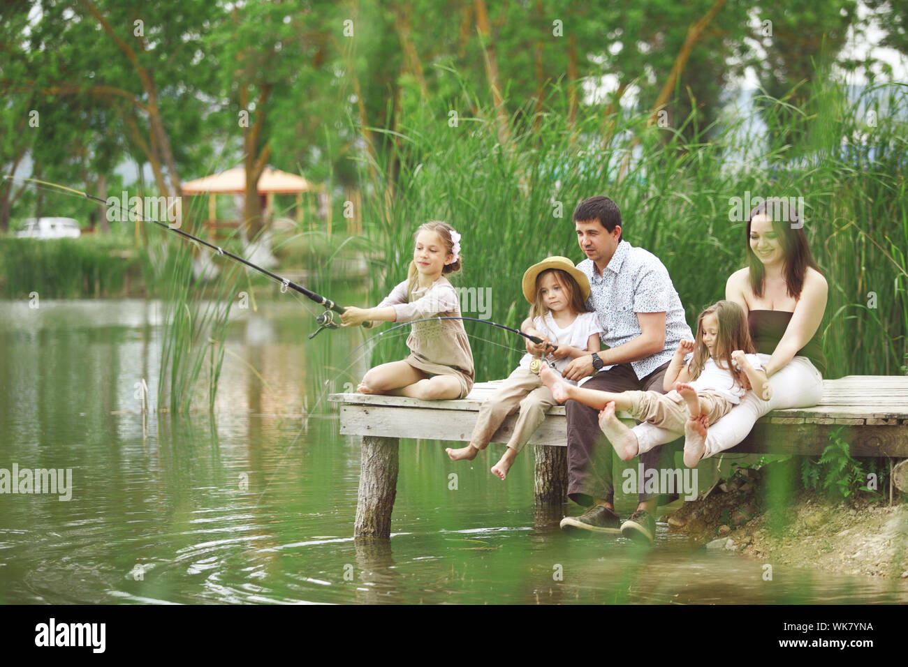 Young happy family with kids fishing in pond in summer Stock Photo - Alamy