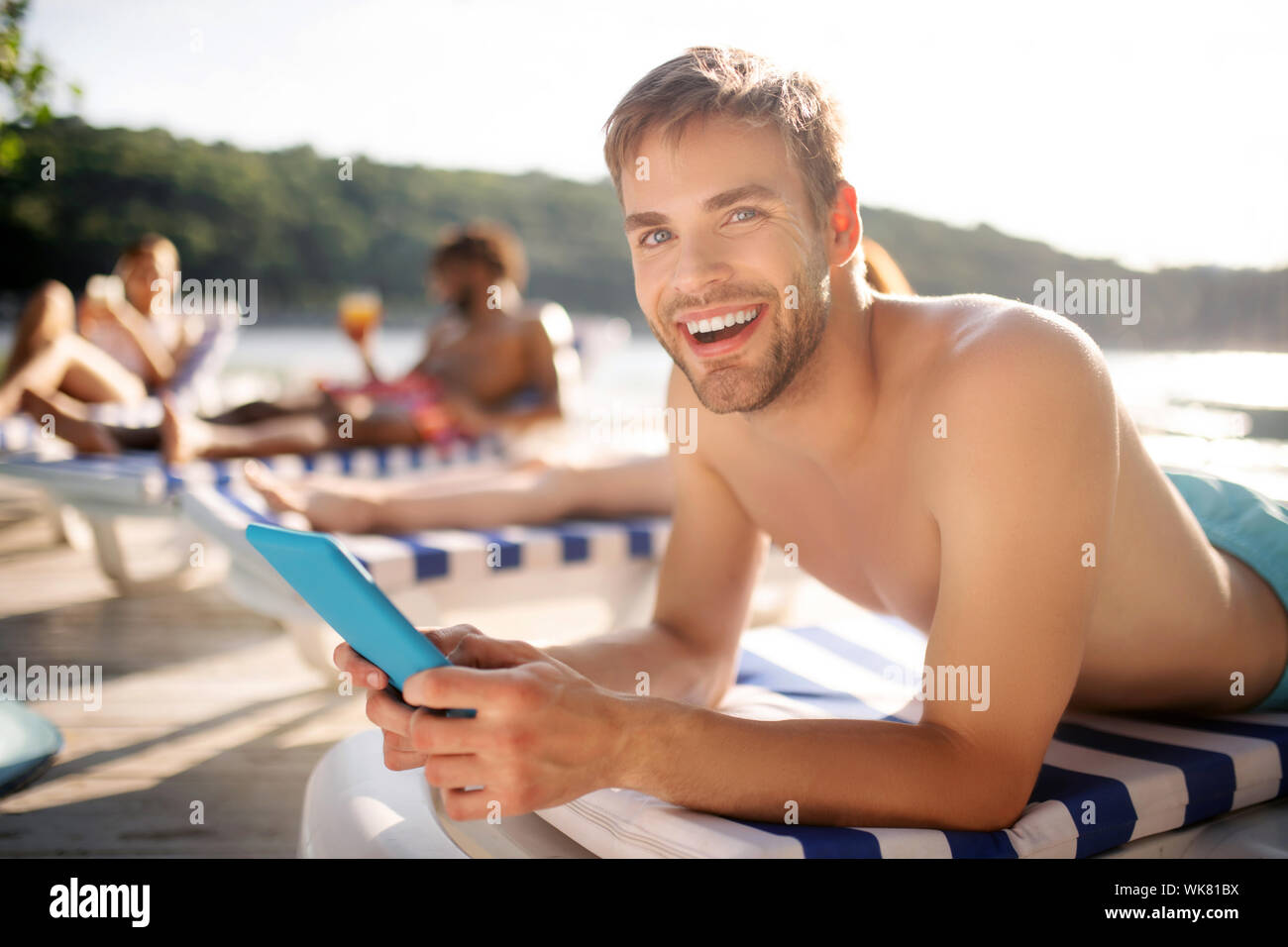 Man holding tablet while having rest near river with friends Stock ...