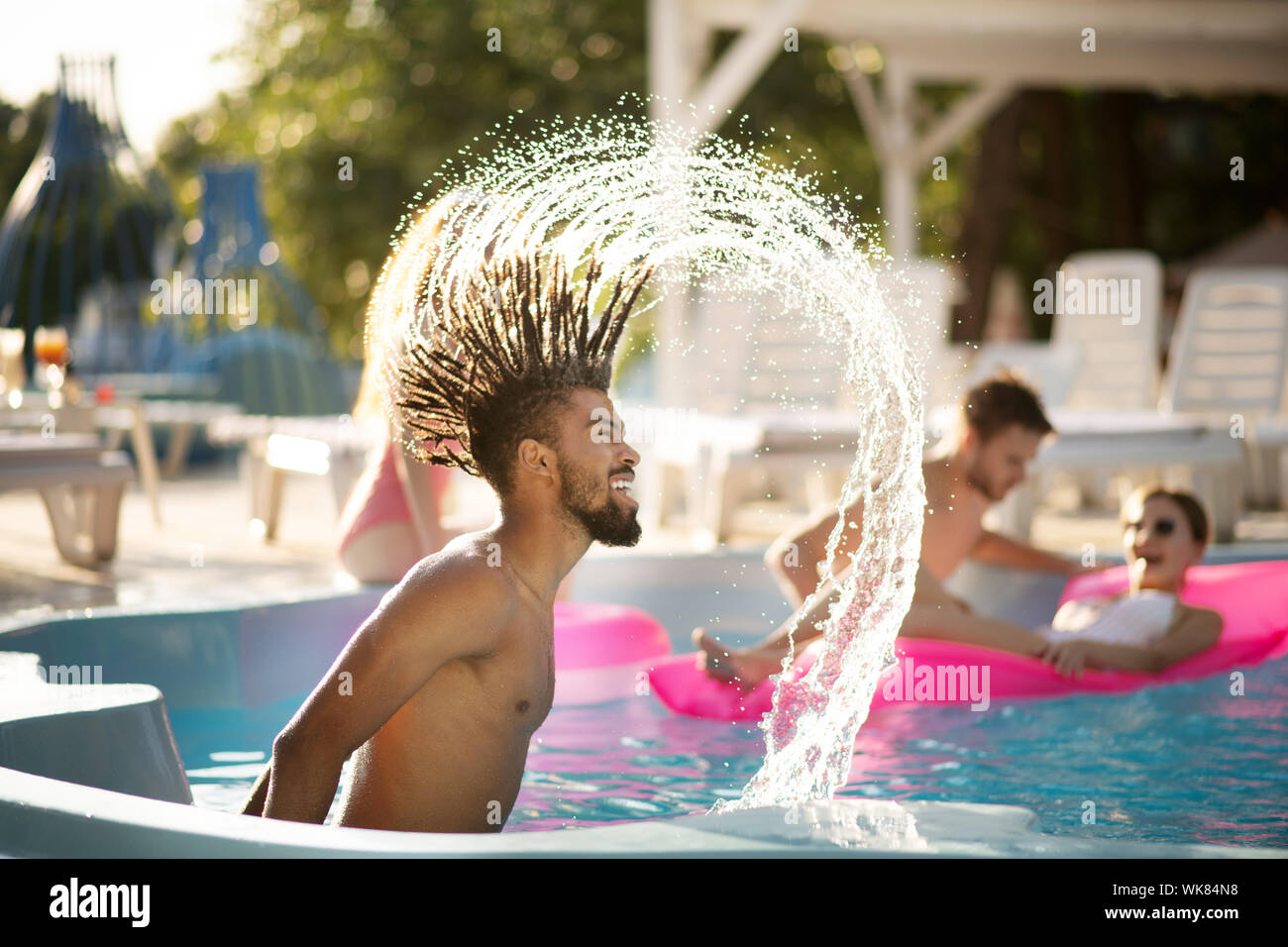 Bearded man with dreadlocks splashing water in pool Stock Photo - Alamy