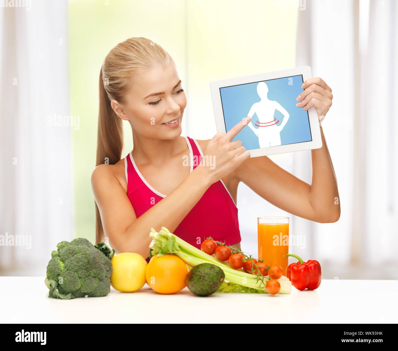 sporty woman with fruits and vegetables pointing at tablet pc Stock ...