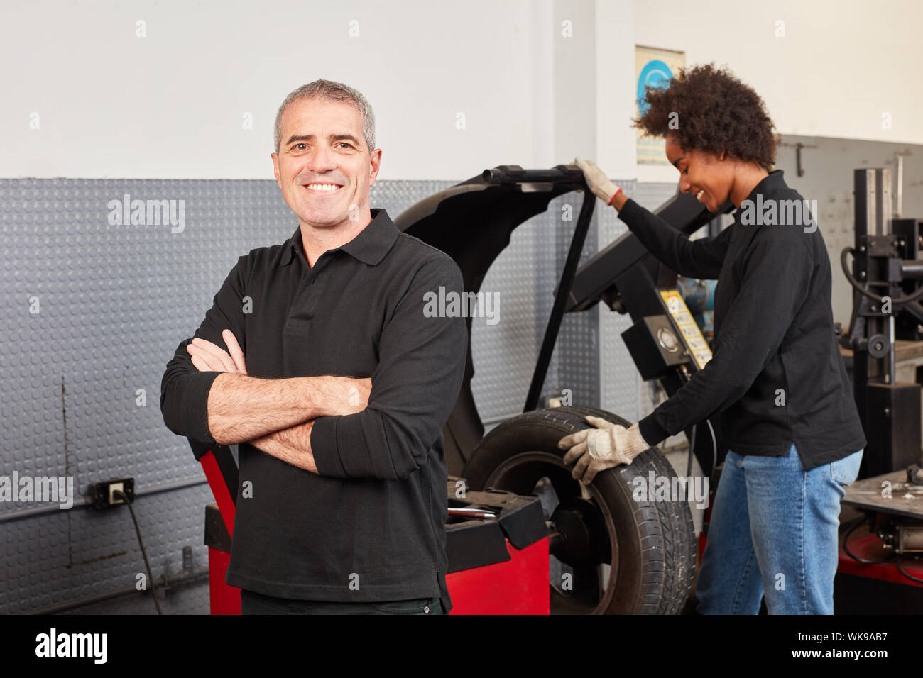 Man as a proud instructor in the car workshop with an African woman as ...