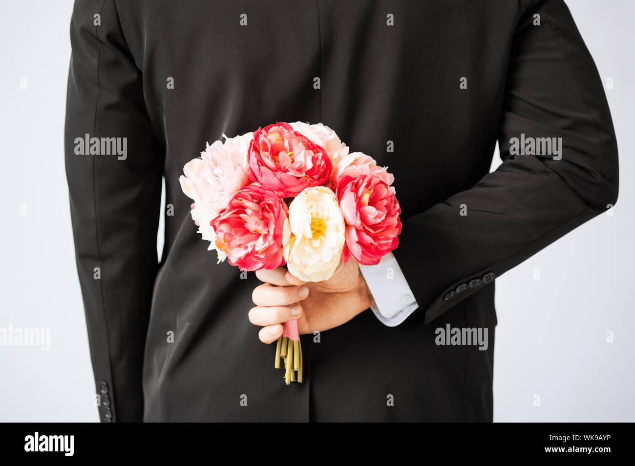 man hiding bouquet of flowers behind his back Stock Photo - Alamy