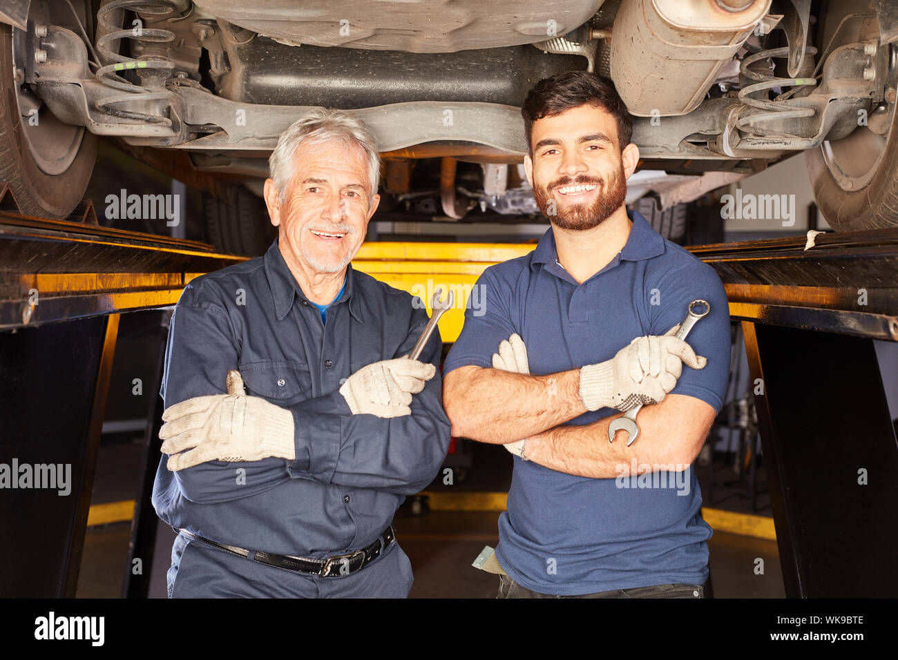 Car master and mechatronics apprentice in front of car on lift in ...