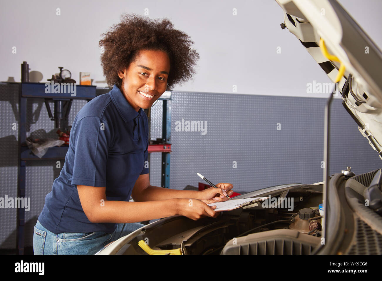 African woman as a mechatronics apprentice with checklist for repair or ...