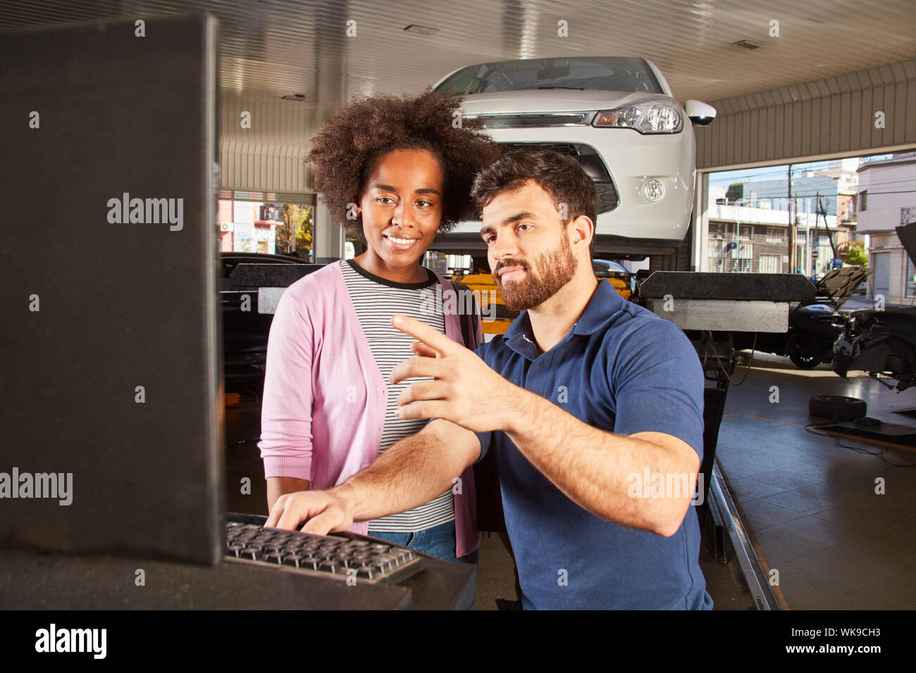Car mechatronics technician explains on the computer the car diagnostic ...