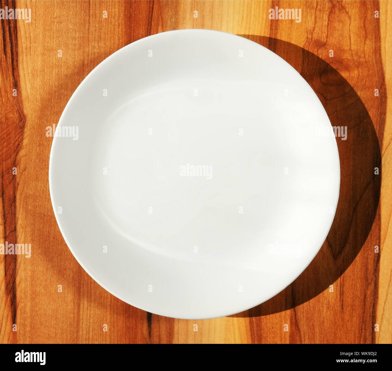 Pure white porcelain dinner plate on kitchen hard wood table with ...
