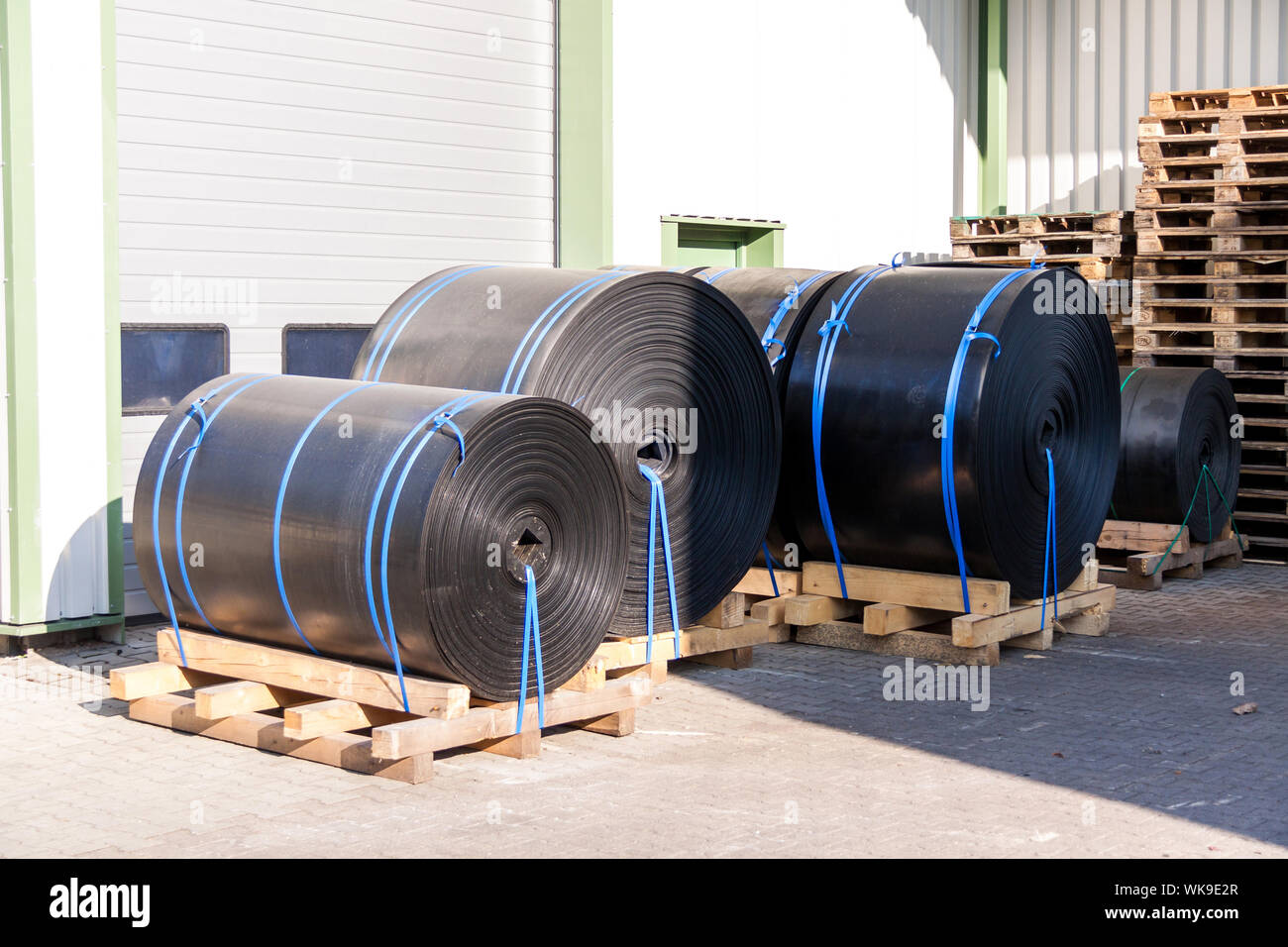 Rolls of black industrial plastic tied to wooden pallets outside a ...