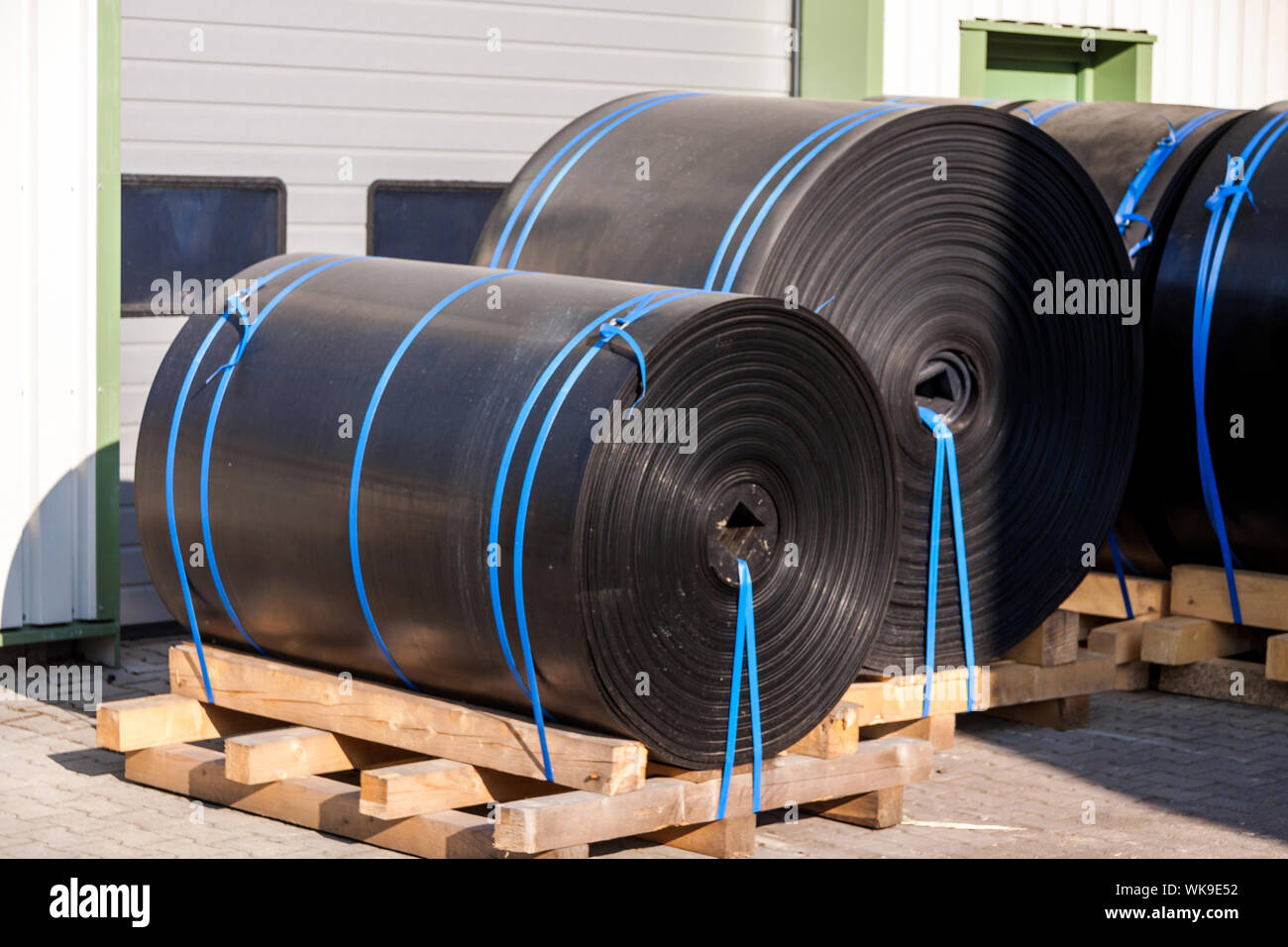 Rolls of black industrial plastic tied to wooden pallets outside a ...