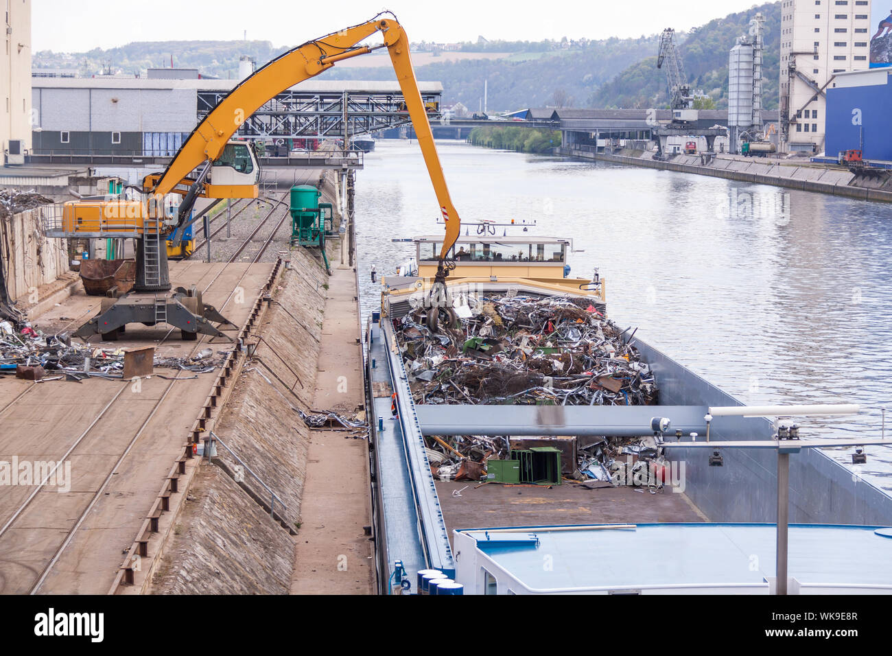 Open barge being loaded or offloaded at a wharf on an urban waterway or ...